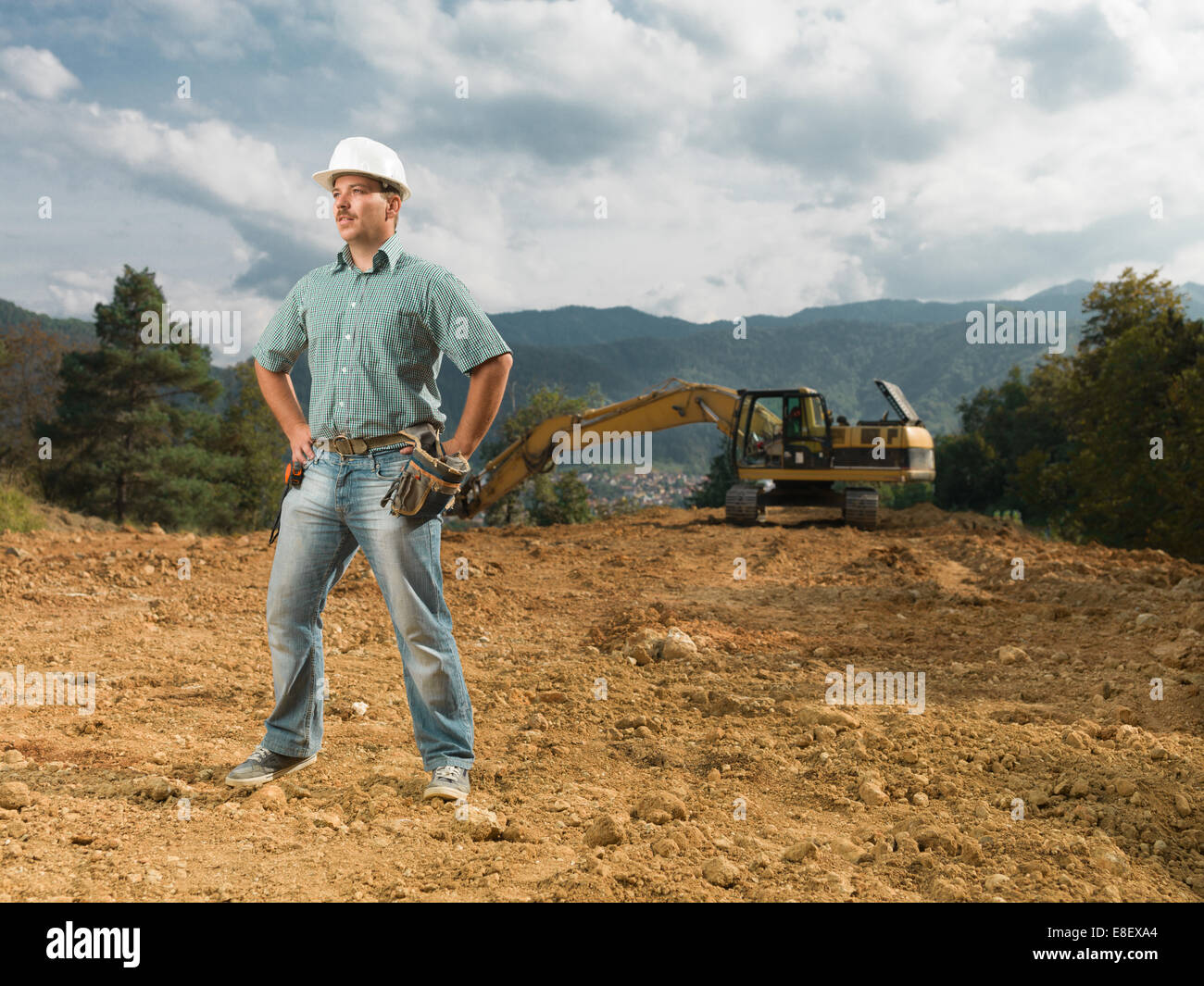 young caucasian male engineer standing on construction site, with ...