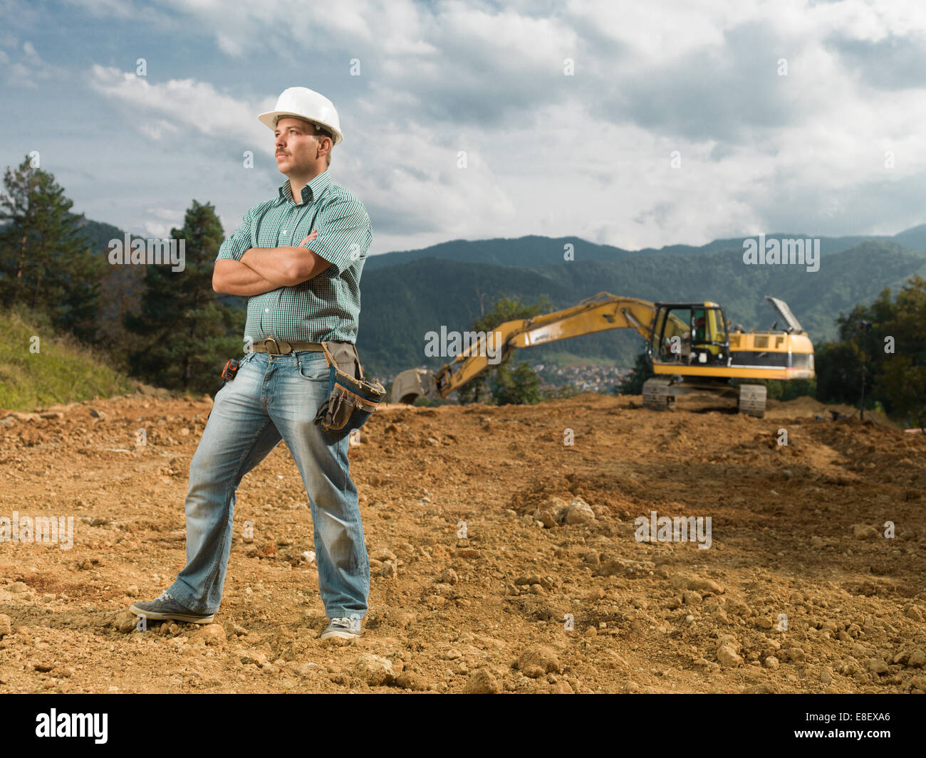 male engineer standing with arms crossed on construction site outdoors ...