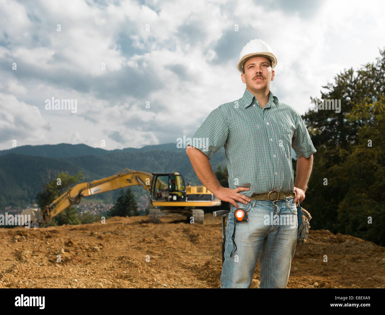 male engineer standing on construction site with excavator in ...