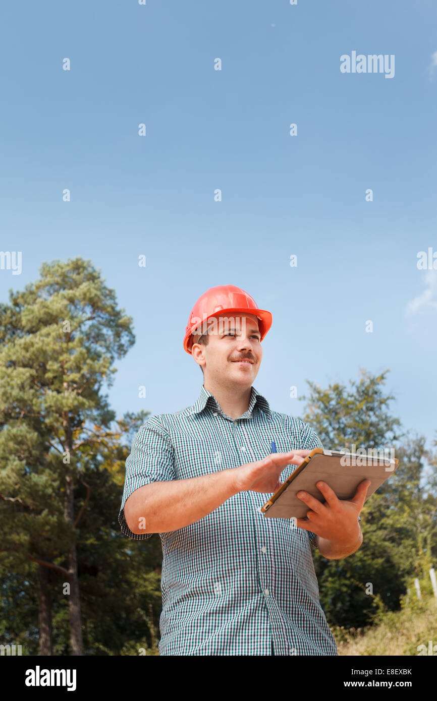 side view of standing engineer holding tablet on construction site ...