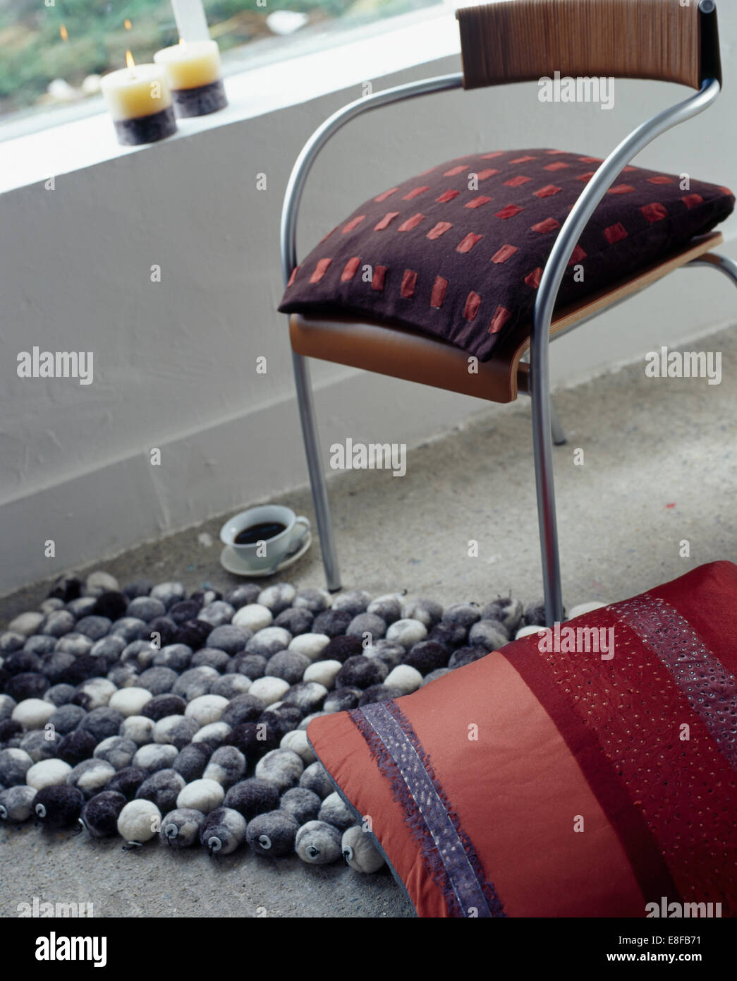 Hand crafted cushion on chrome chair in room with gray hand made bobble ...