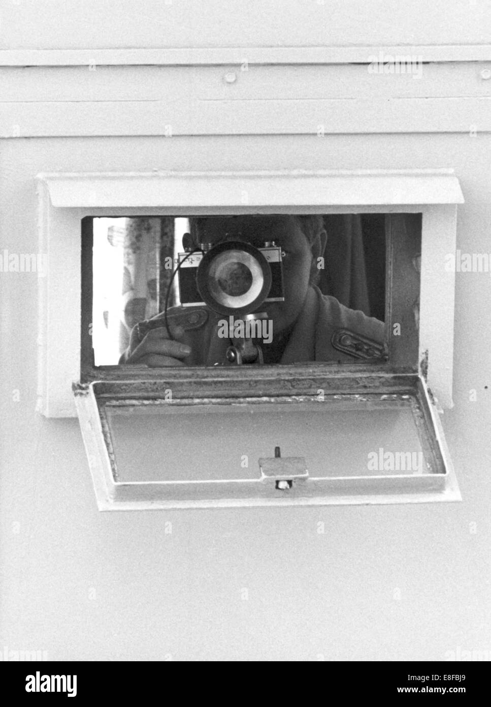 A border soldier of the GDR has a look through a camera towards the ...