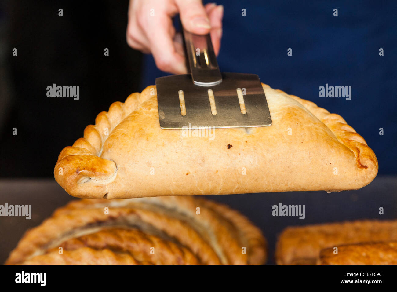 Picture of a Cornish pasty held by serving tongs in the display of a ...