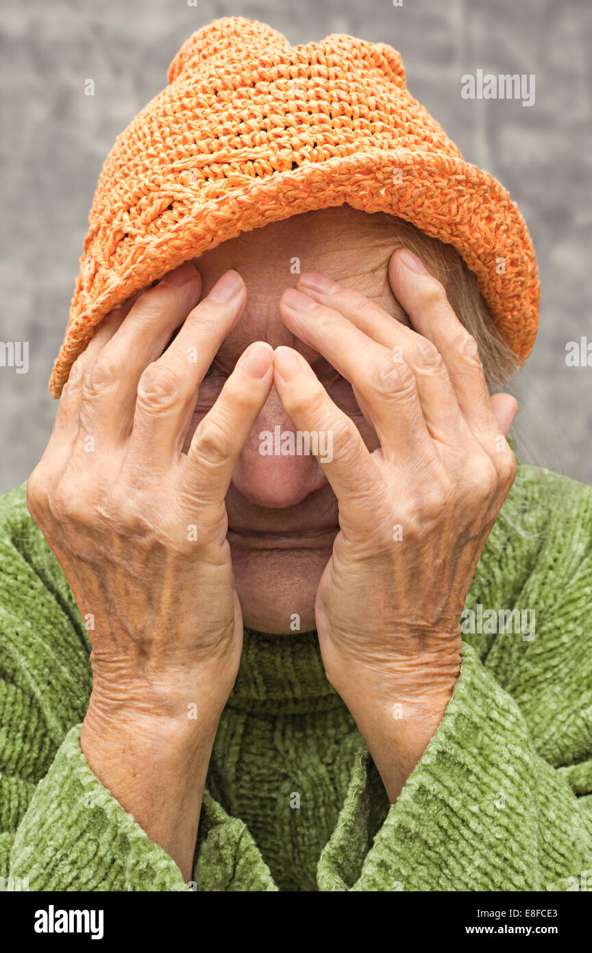 Scared and worried elderly woman covering her face with hands Stock ...