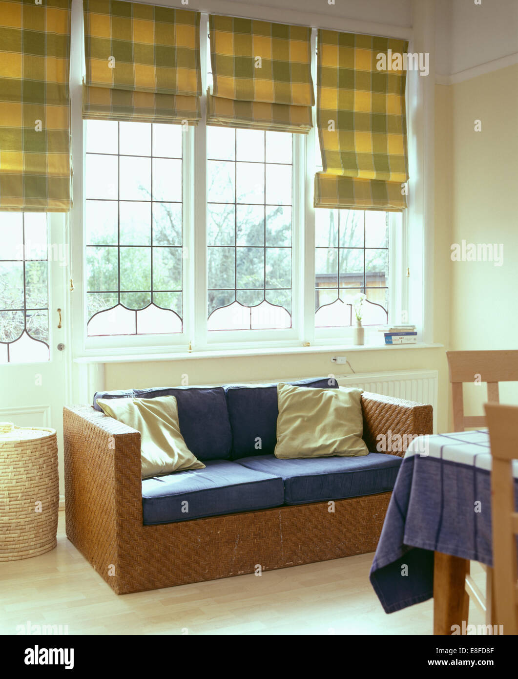 Yellow checked blinds on window above wicker sofa with blue cushions in ...