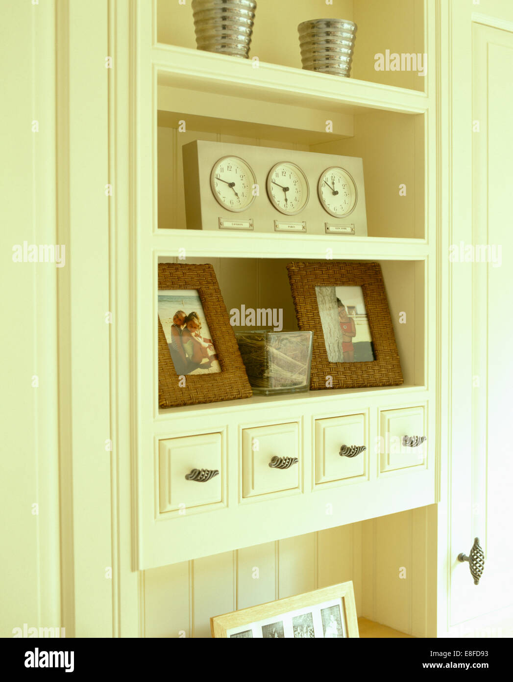 Close-up of triple-face clock on cream shelves with photographs and ...