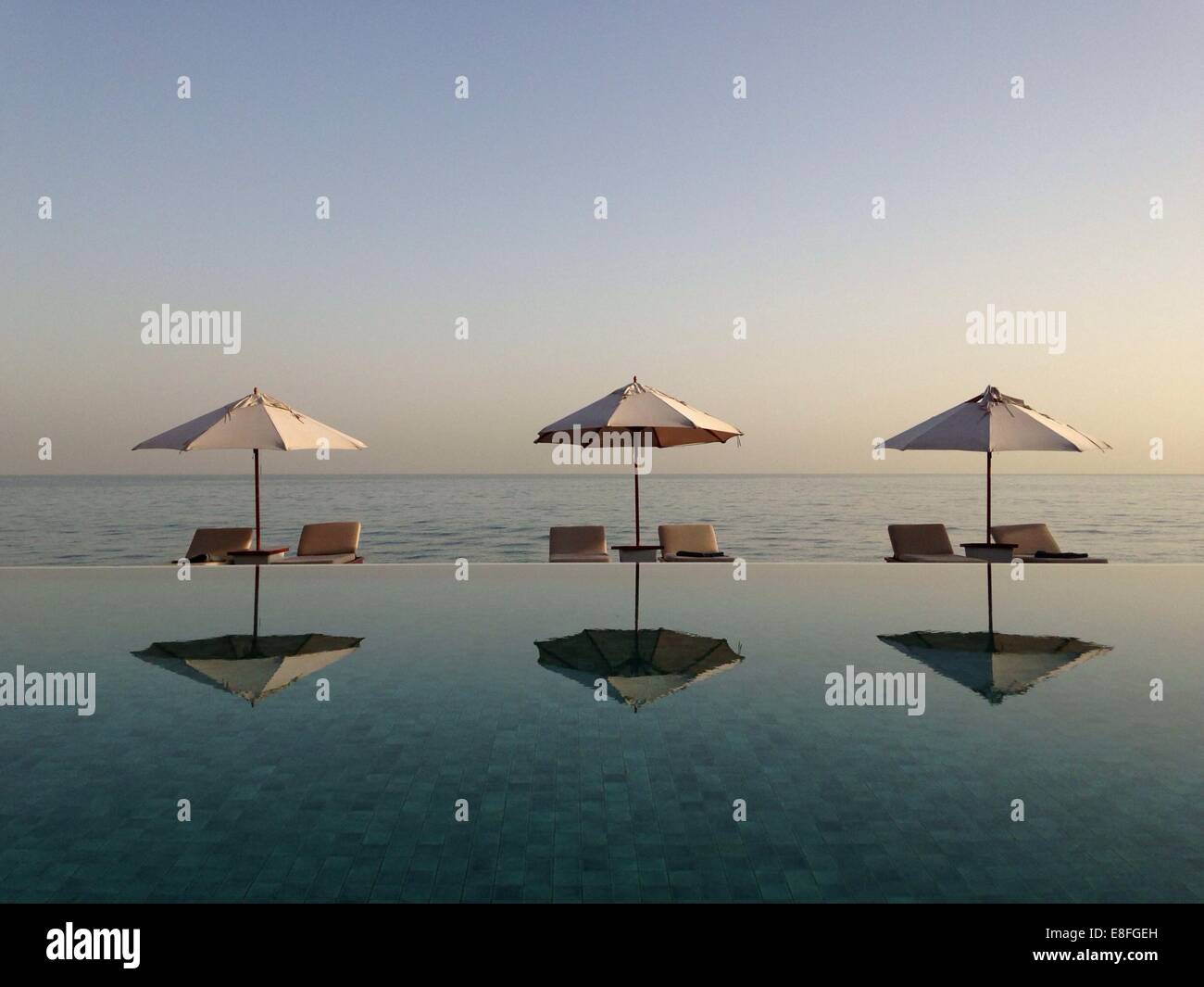 Parasols and sun lounger reflections in a swimming pool Stock Photo - Alamy