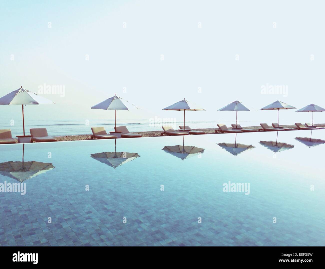 Parasols reflected in a swimming pool with beach behind Stock Photo - Alamy