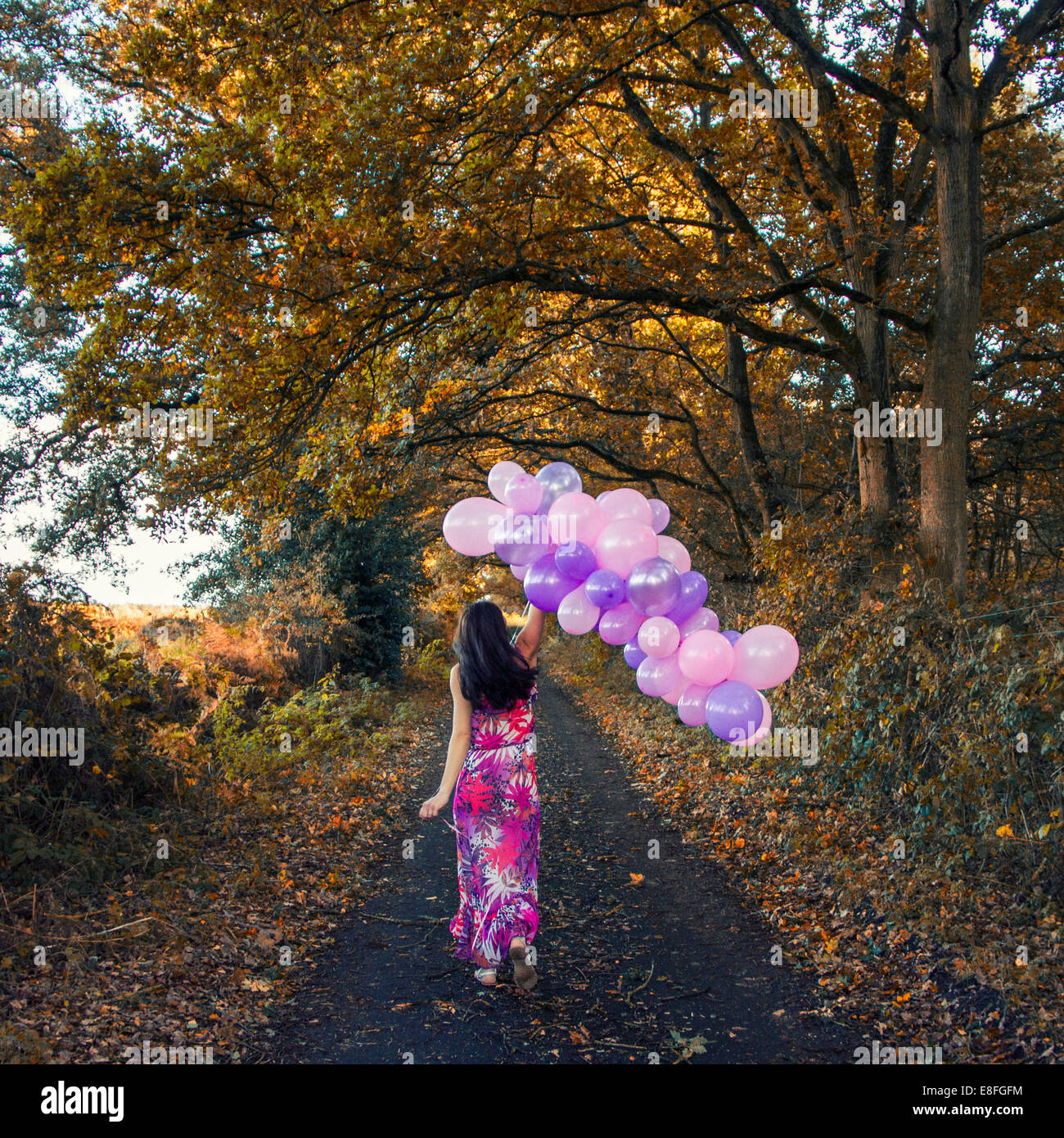 Woman walking on path and holding balloons Stock Photo - Alamy