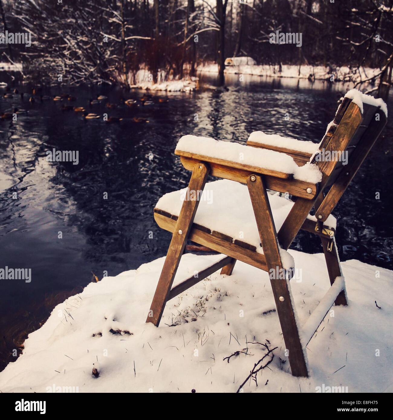 Snow covered chair by lake in winter Stock Photo - Alamy