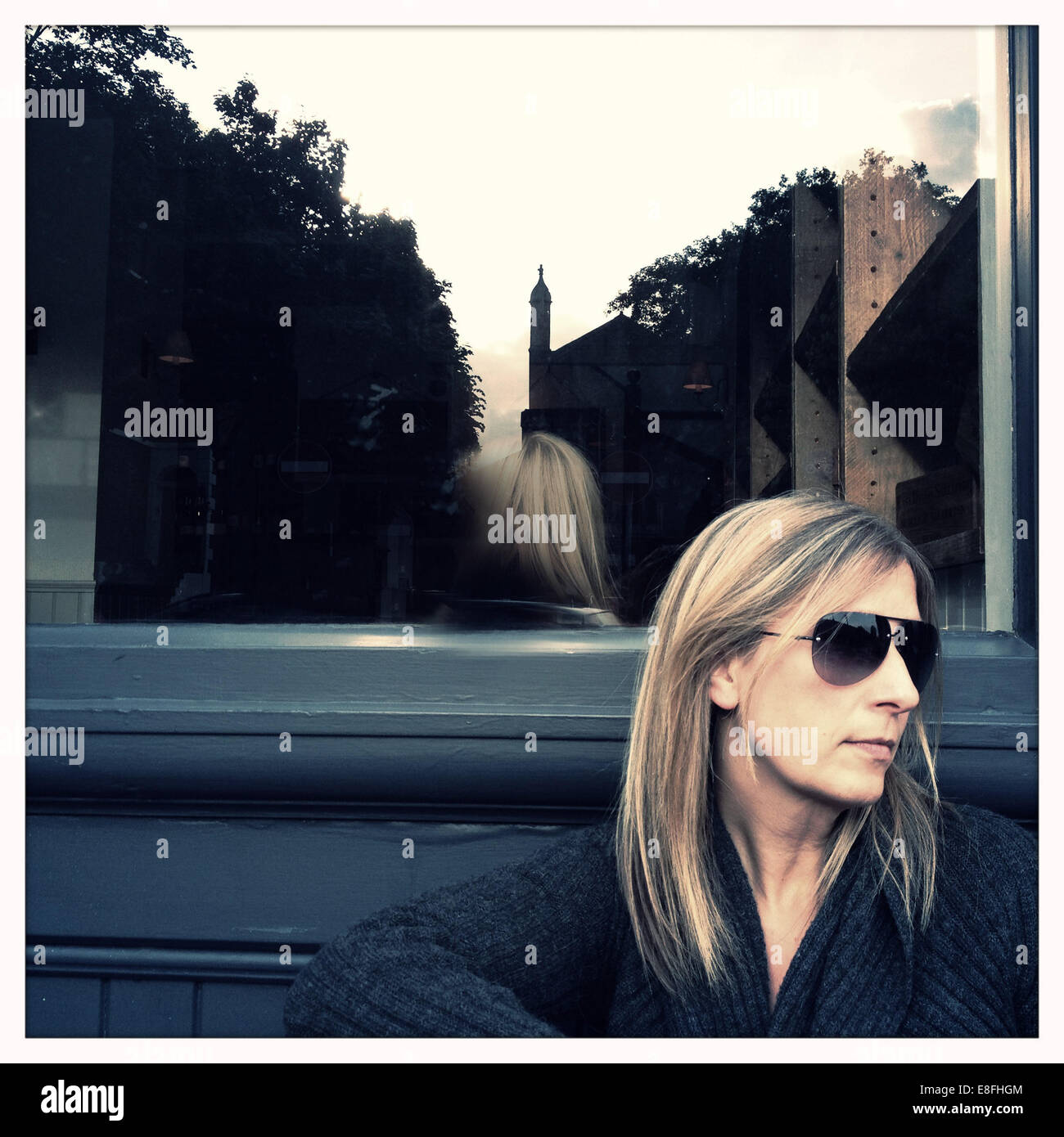 Portrait of a woman sitting in front of a window in the sun Stock Photo ...