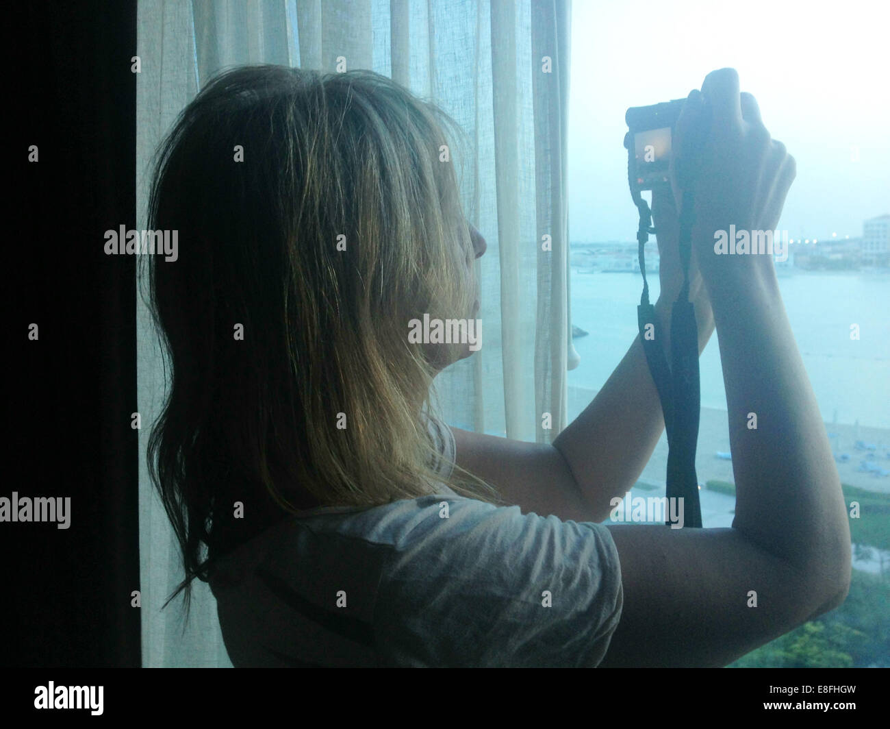Woman taking photograph out of a window Stock Photo - Alamy