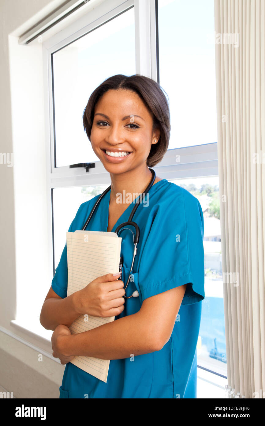 Portrait of a young female doctor leaning holding medical notes Stock ...