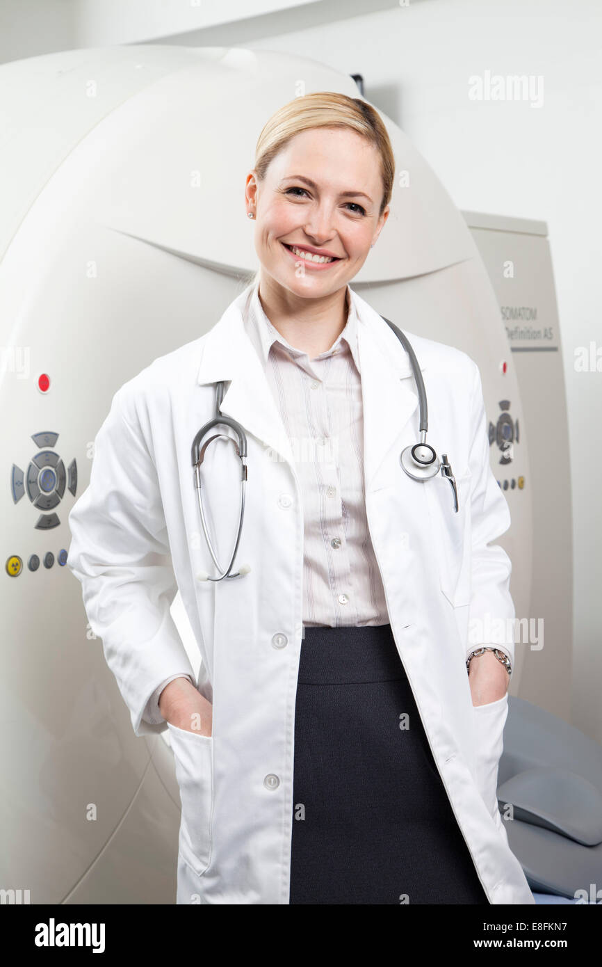 Portrait of a smiling doctor standing next to an MRI Scanner in a ...