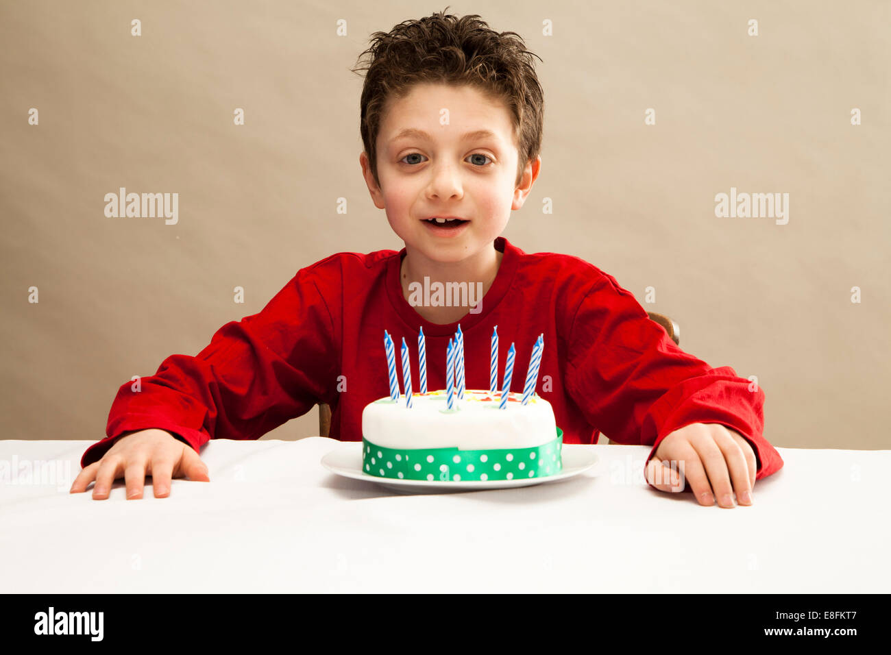 Boy sitting at table with birthday cake Stock Photo - Alamy
