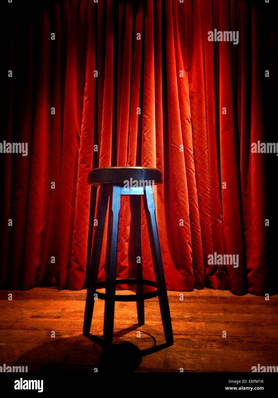 Stool on a stage in front of red curtain Stock Photo - Alamy
