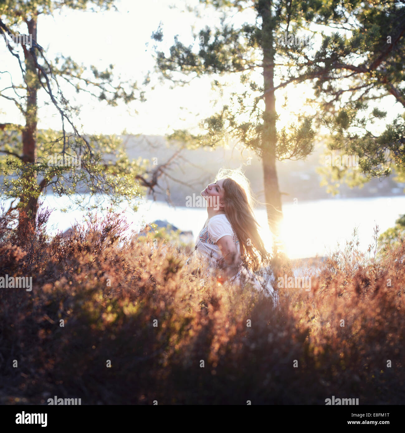 Woman standing by a lake throwing her head back hi-res stock ...