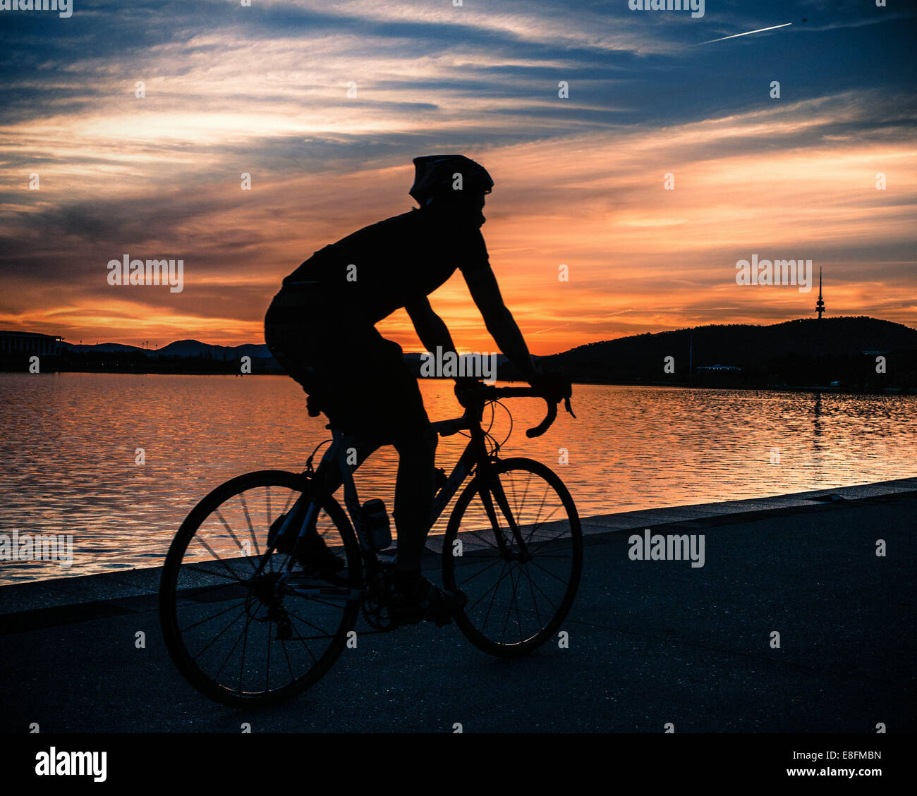 Silhouette of cyclist at sunset near Lake Burley Griffin, Canberra ...