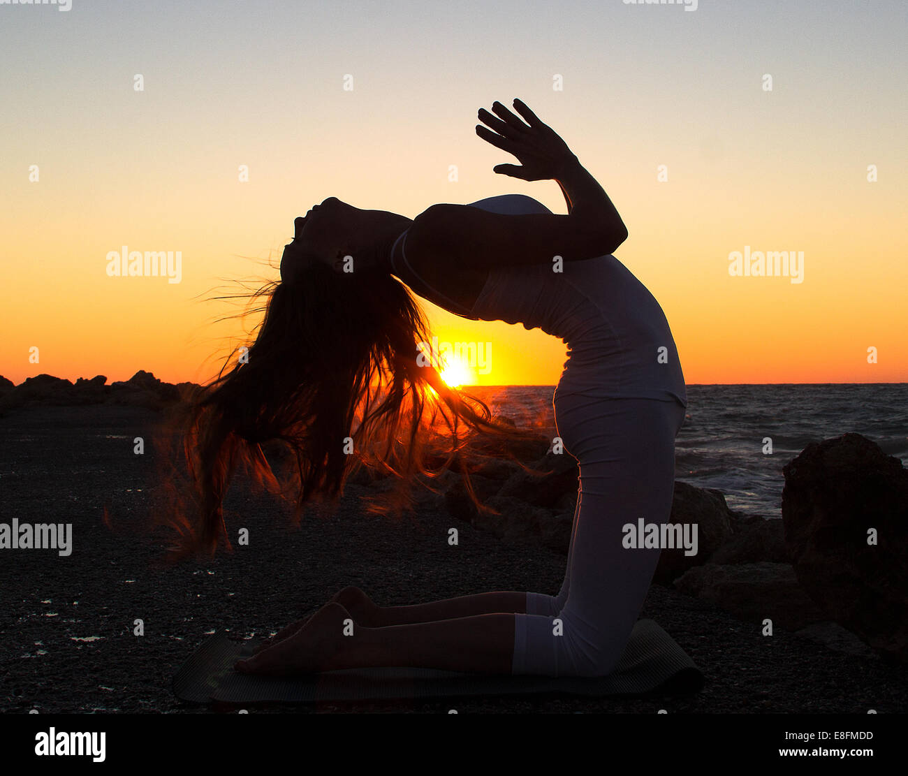 Woman practicing yoga on beach at sunset Stock Photo - Alamy