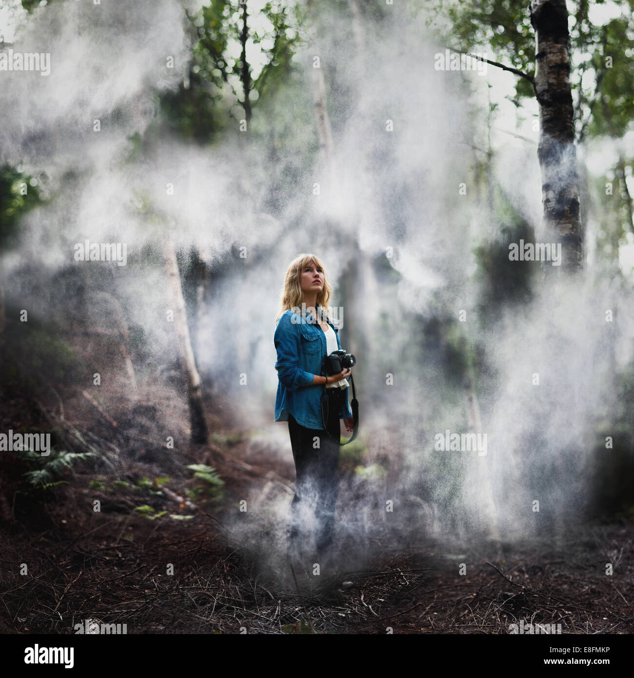 Woman standing in a misty forest holding a camera, Norway Stock Photo ...