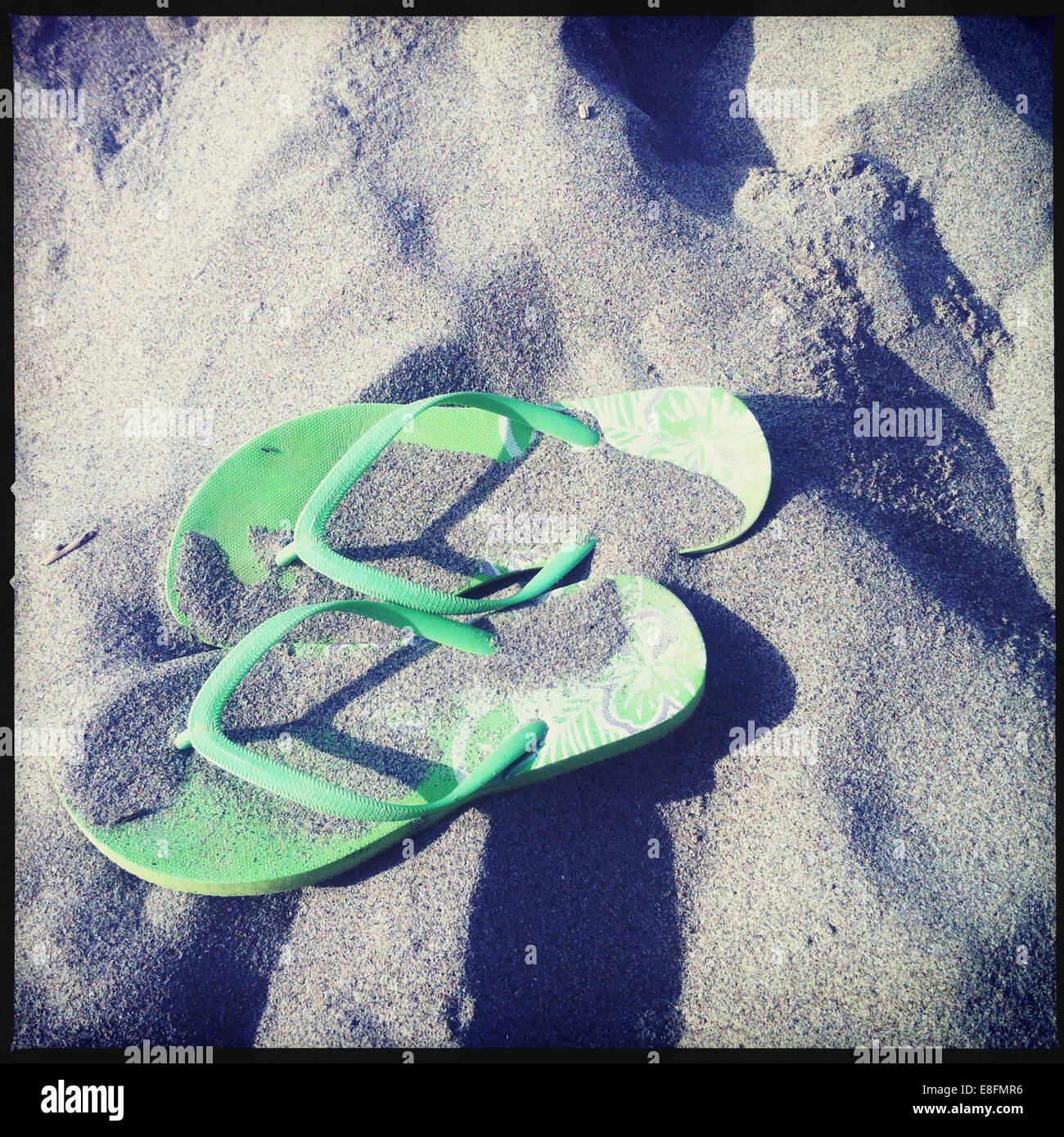 Overhead view of pair of Green flip-flops on sand Stock Photo - Alamy