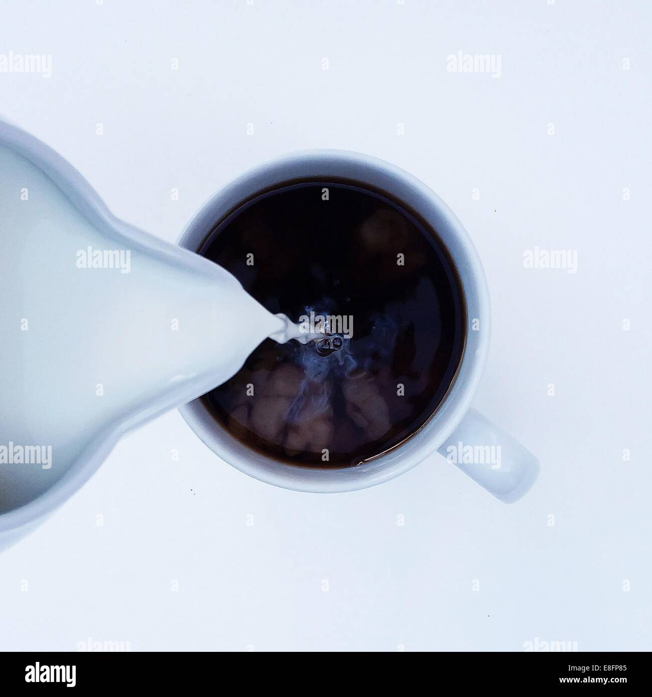 Overhead view of milk being poured into cup of coffee Stock Photo - Alamy