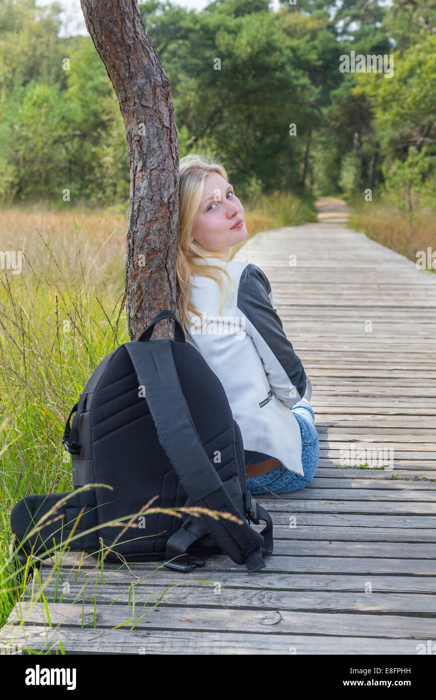 Girl sitting on wooden path in nature Stock Photo - Alamy