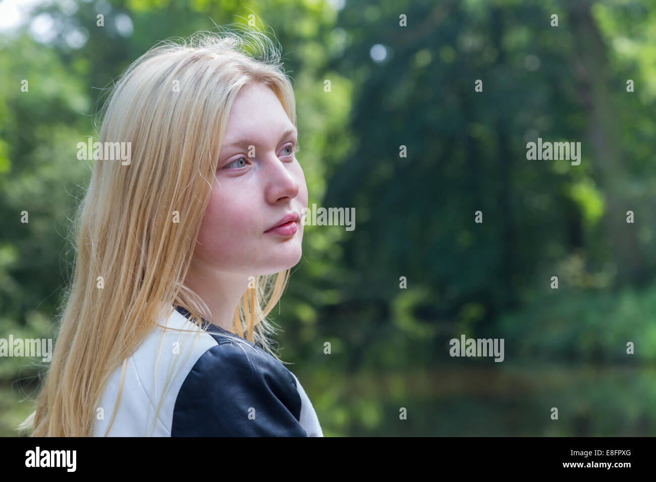 Head of blond girl with water and trees Stock Photo - Alamy