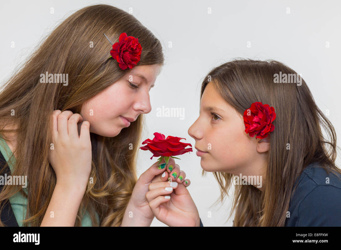 Portrait of two girls smelling red rose Stock Photo - Alamy