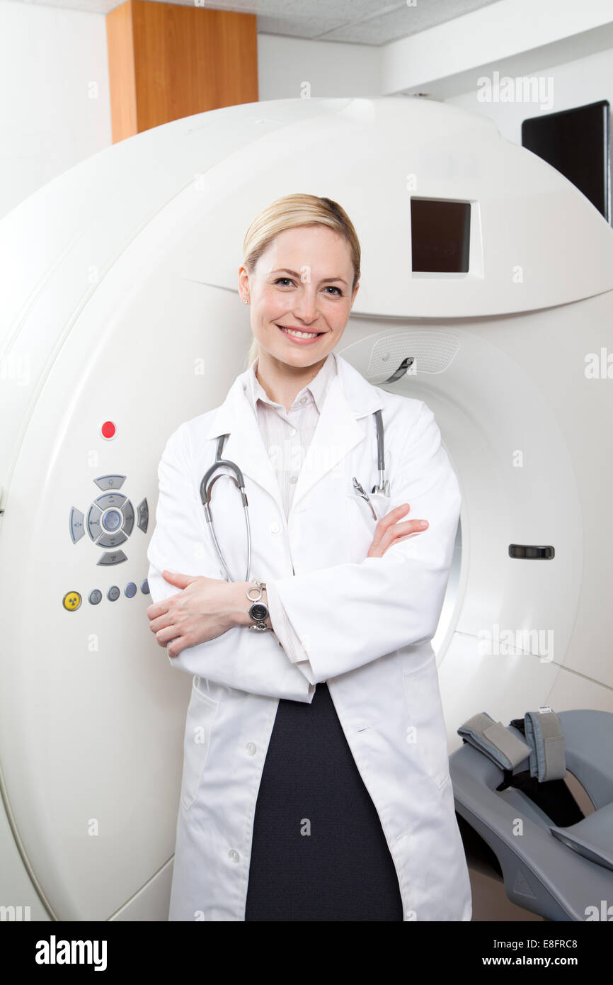 Portrait of a smiling doctor standing next to an MRI Scanner in a ...