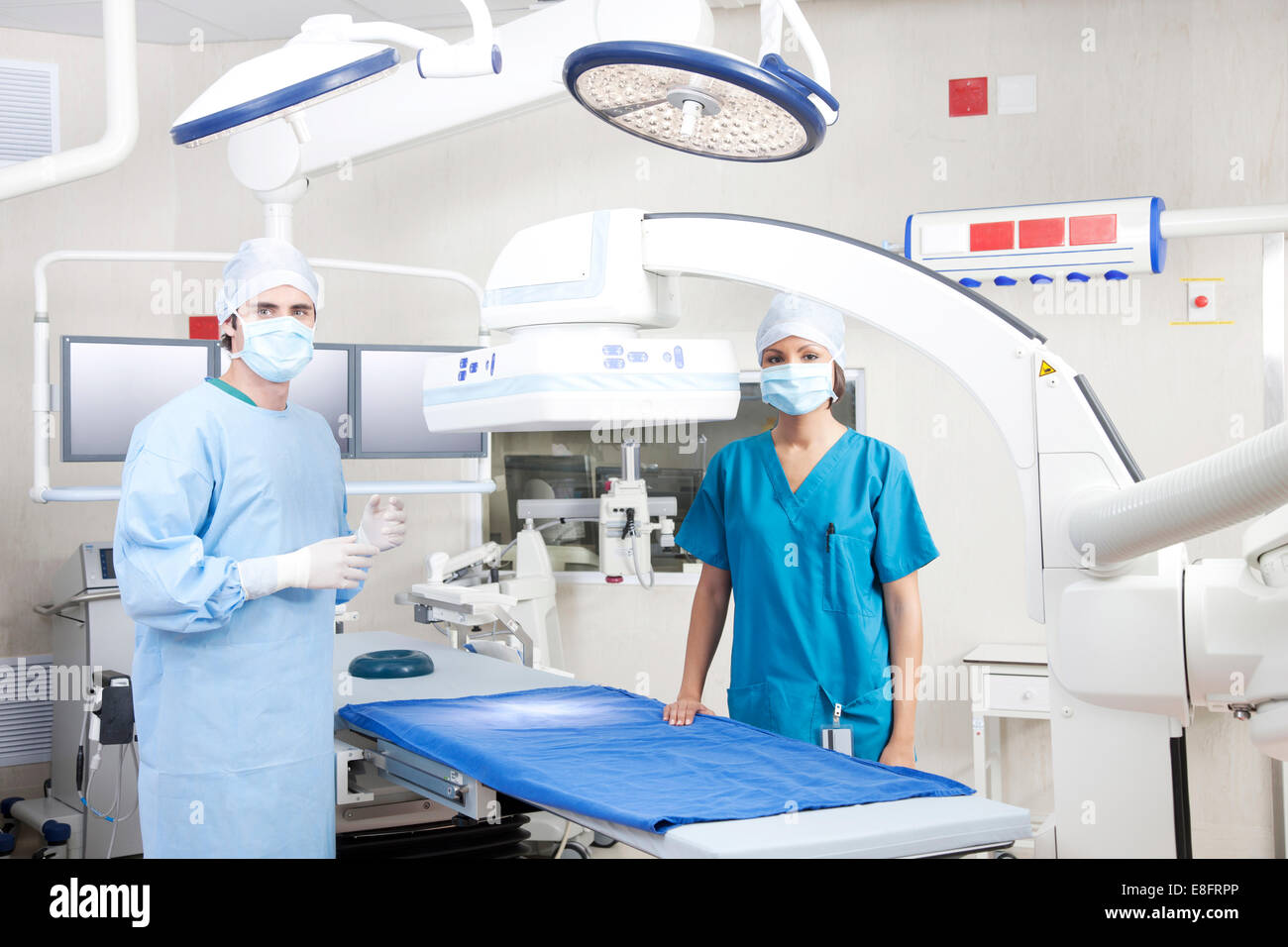 Surgeon and nurse in operating theatre with robotic imaging system ...