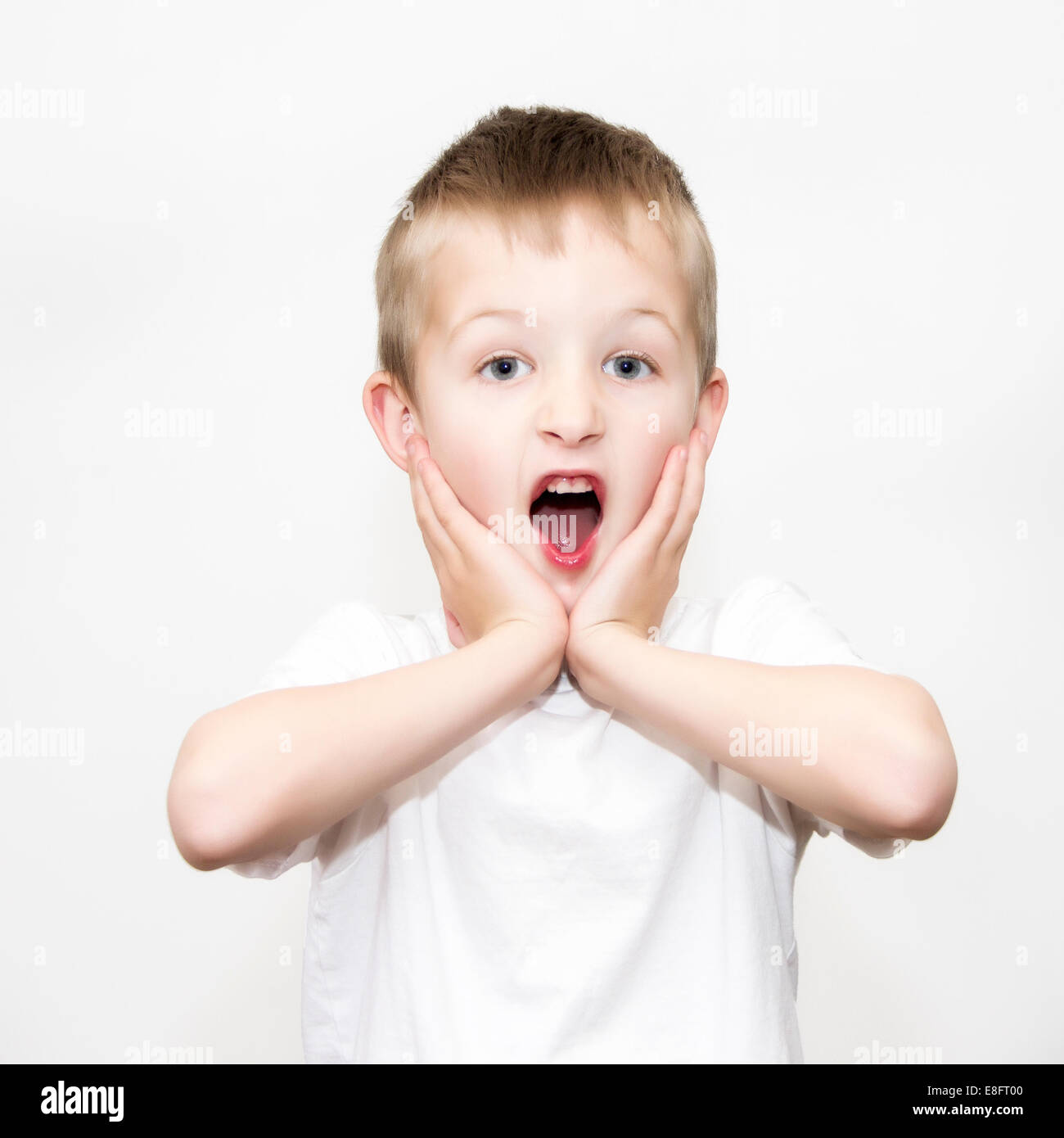 Shocked boy holding hands to face Stock Photo - Alamy