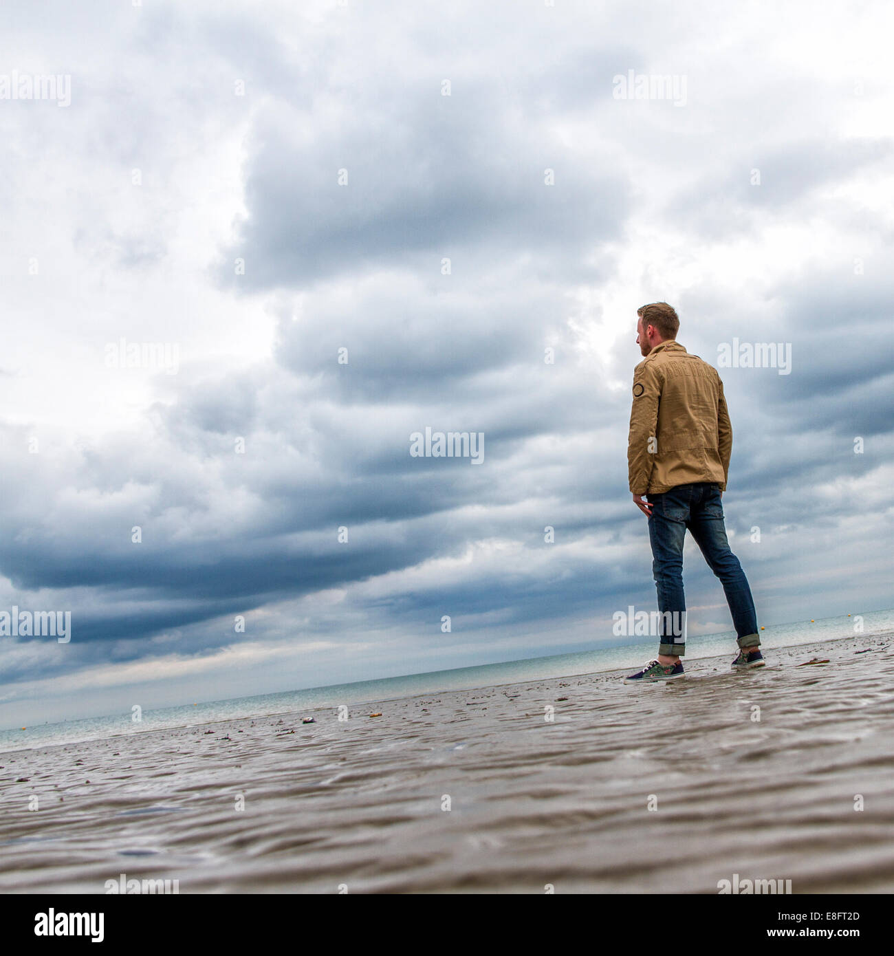 Man on beach looking at view Stock Photo - Alamy