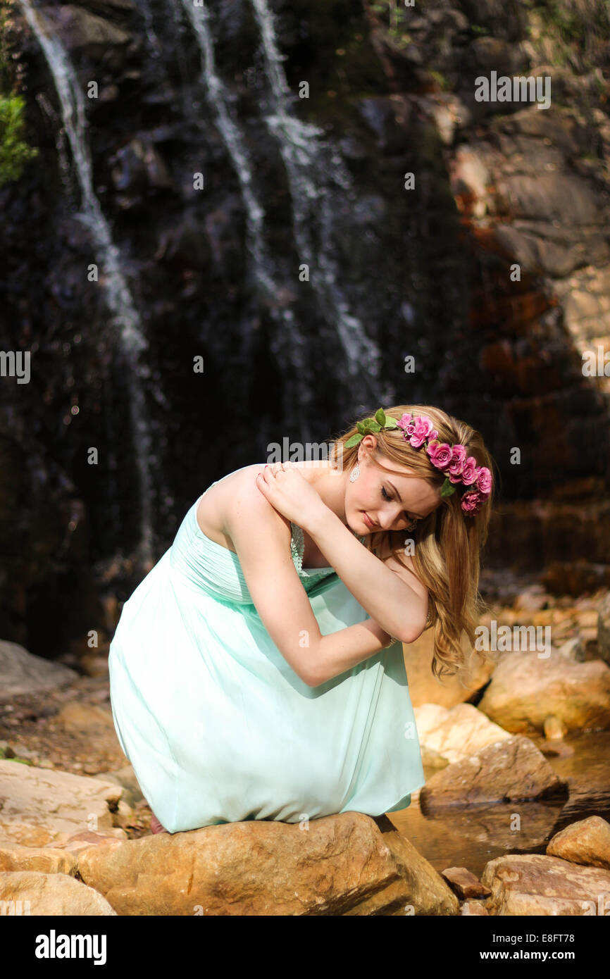 Woman crouching by waterfall Stock Photo - Alamy