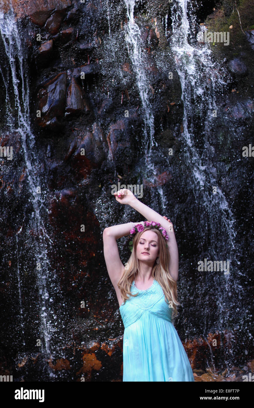 Woman standing by waterfall with raised arms Stock Photo - Alamy
