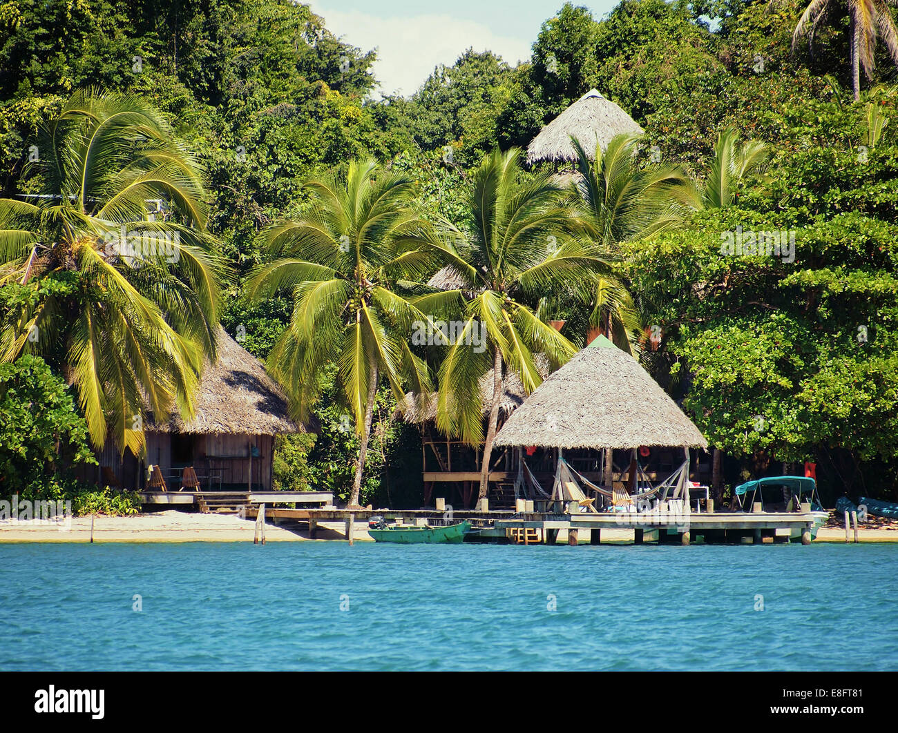 Eco resort on a Caribbean beach with thatched huts and lush tropical ...