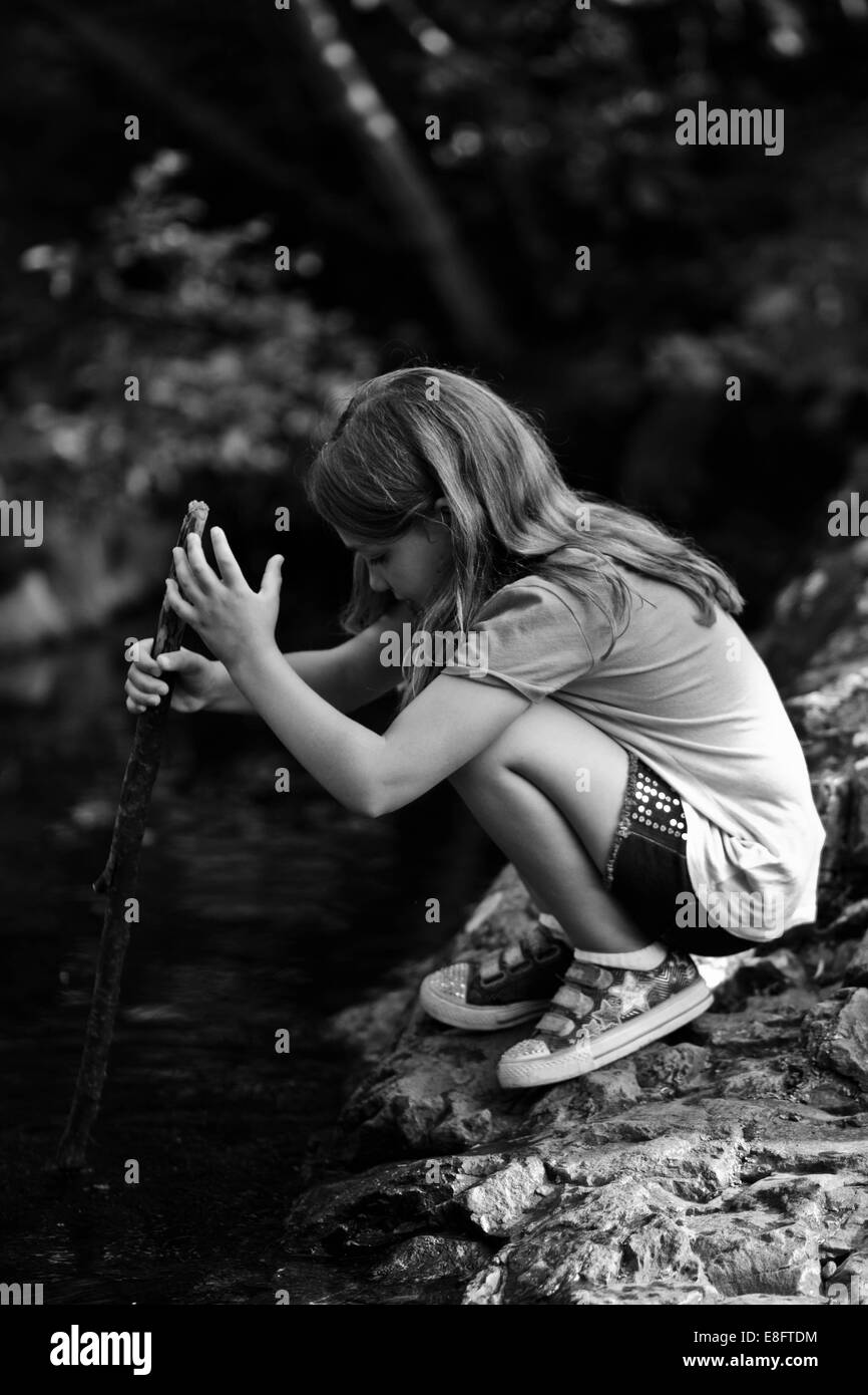 Girl with a stick playing by river Stock Photo - Alamy