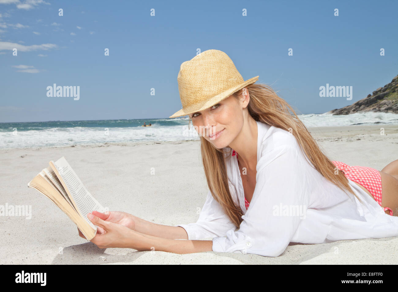 Young woman lying on the beach reading, Cape Town, Western Cape, South ...