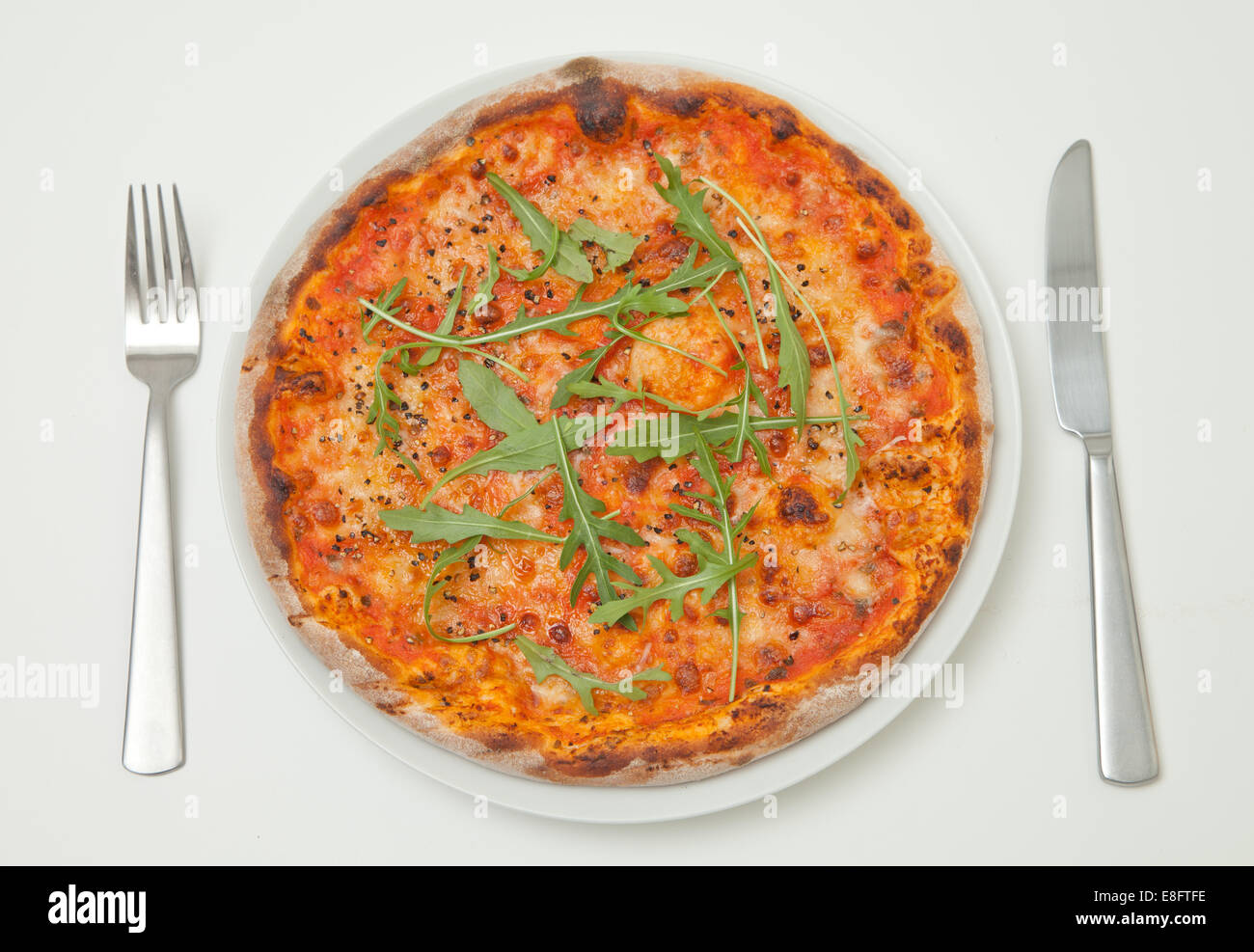 Overhead view of a cheese and tomato pizza with rocket on a plate Stock ...