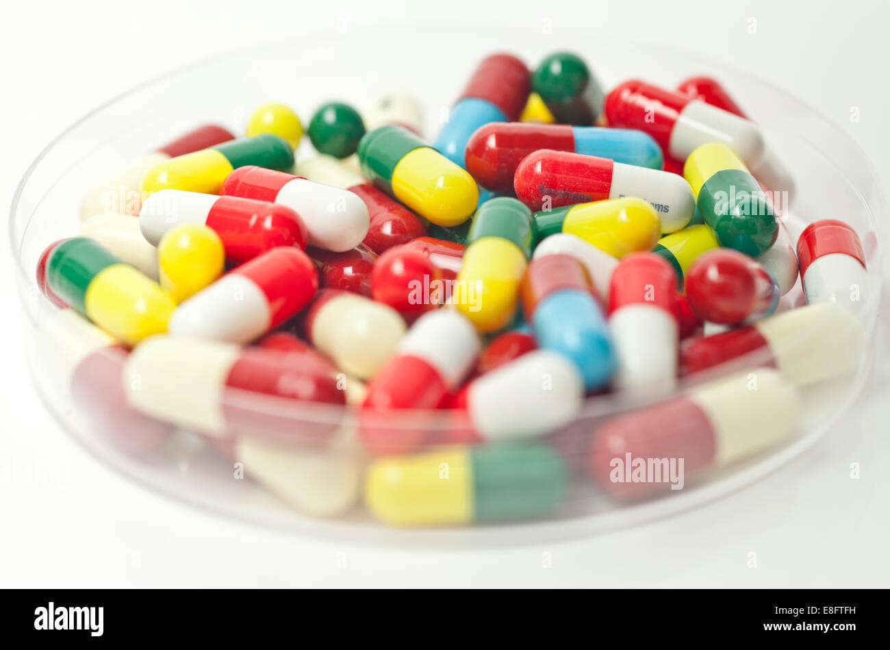 Close-up of a transparent petri dish filled with multi coloured pills ...