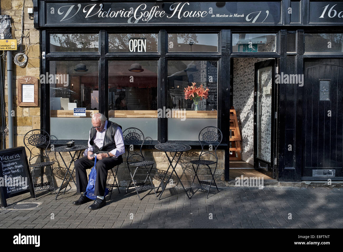 Pavement cafe. Man sat alone at a pavement coffee shop. Moreton in the ...