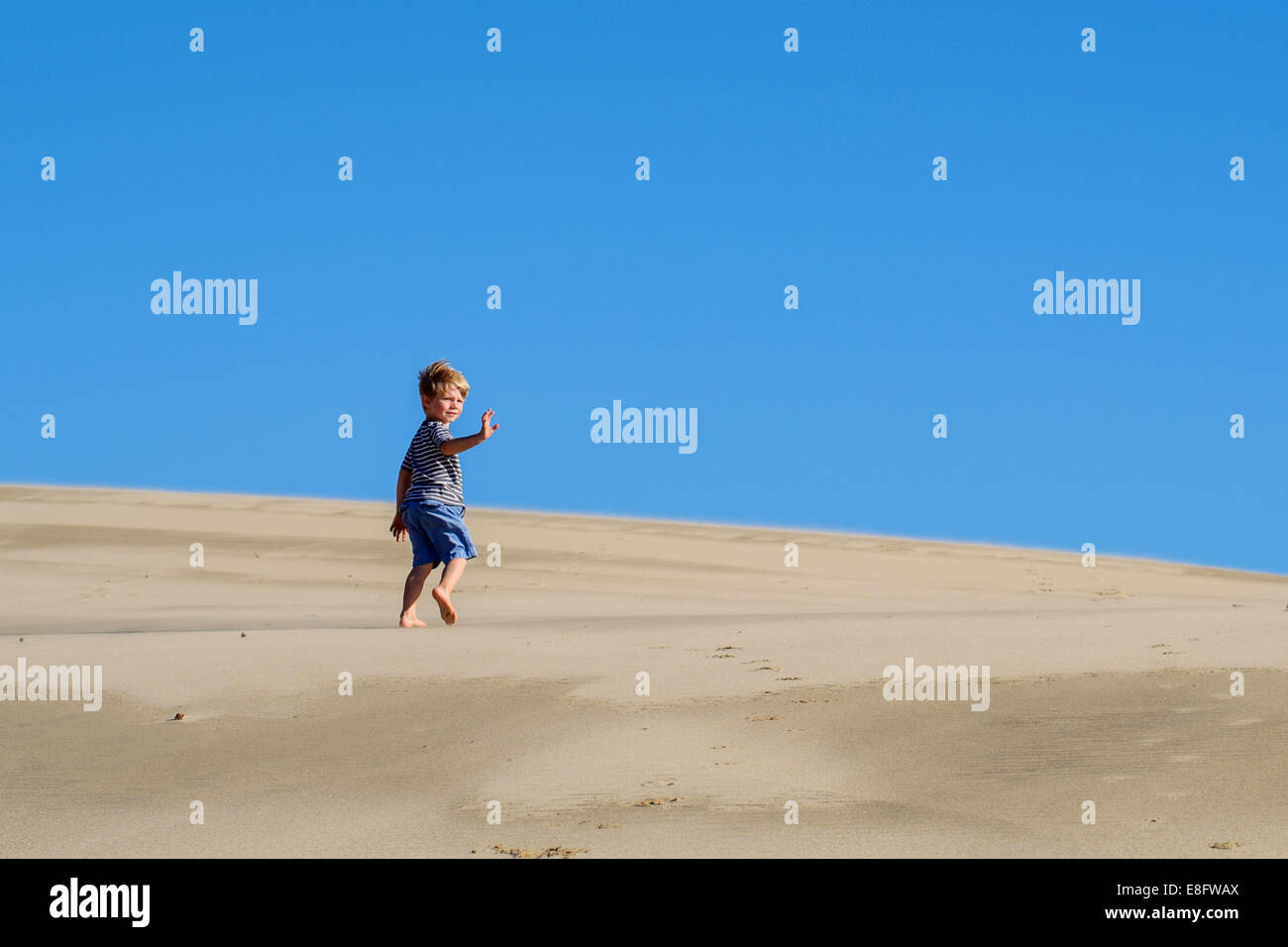 Boy running on beach looking over his shoulder Stock Photo - Alamy