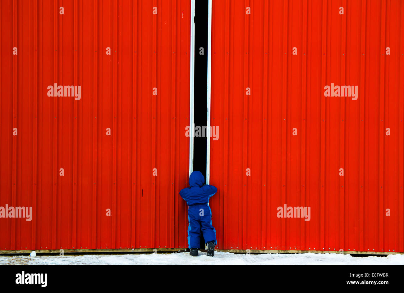 Boy looking through gap in a barn door, USA Stock Photo - Alamy