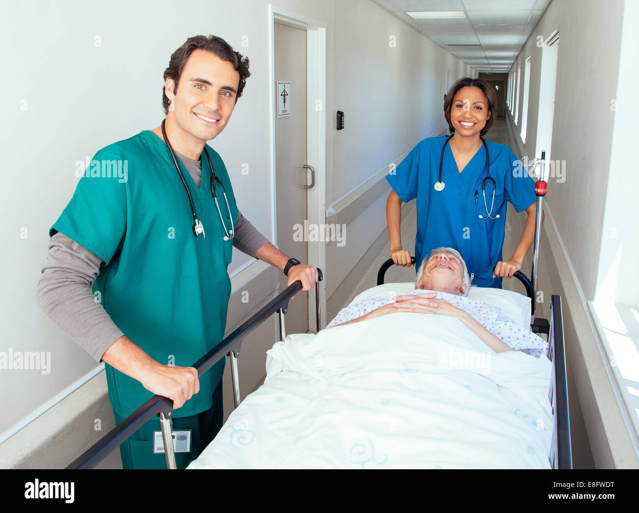 Two doctors pushing patient in bed along hospital corridor Stock Photo ...
