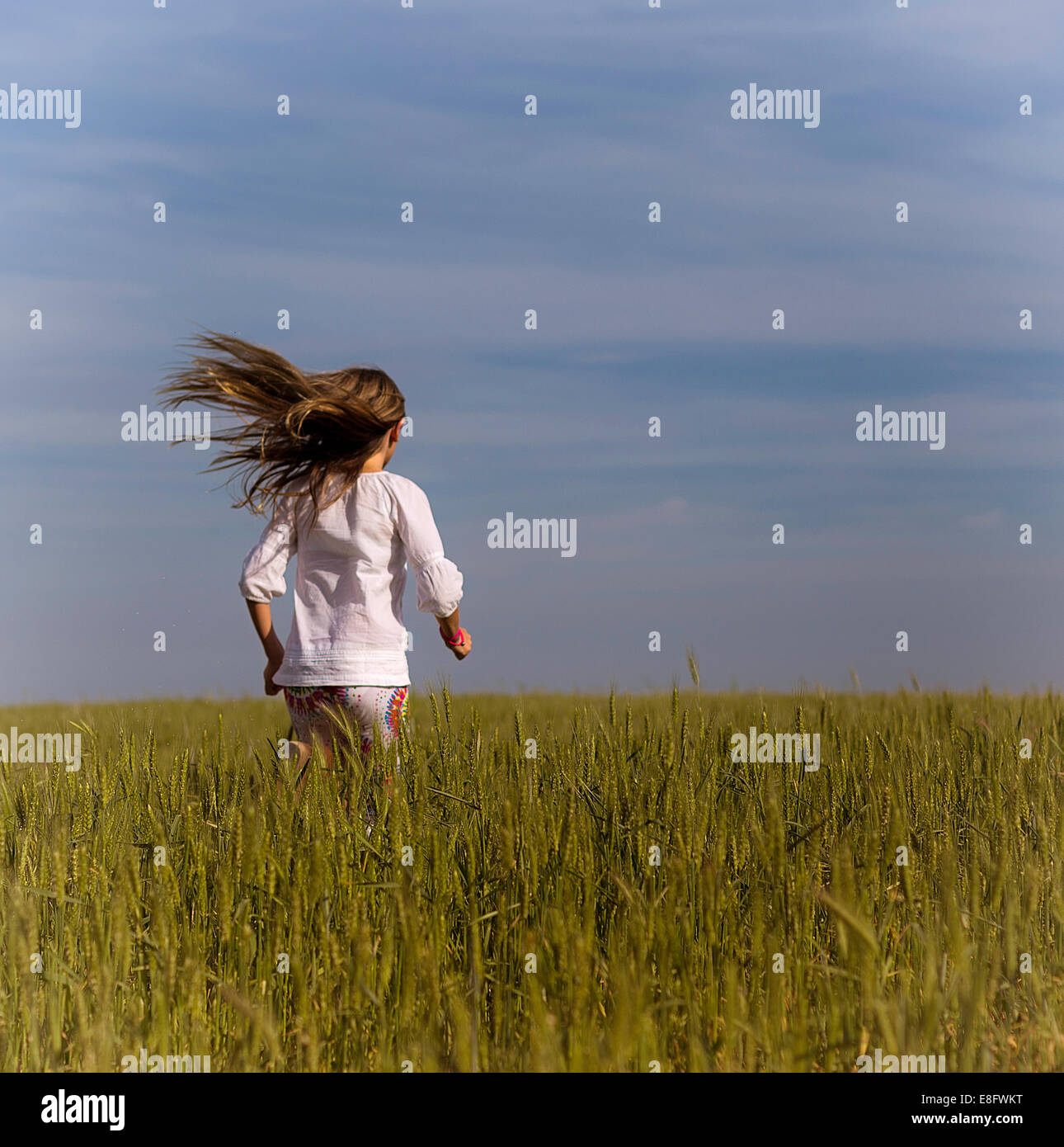 Girl running through a field Stock Photo - Alamy