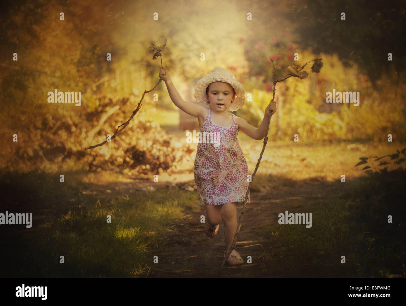 Girl running in a park carrying sticks Stock Photo - Alamy