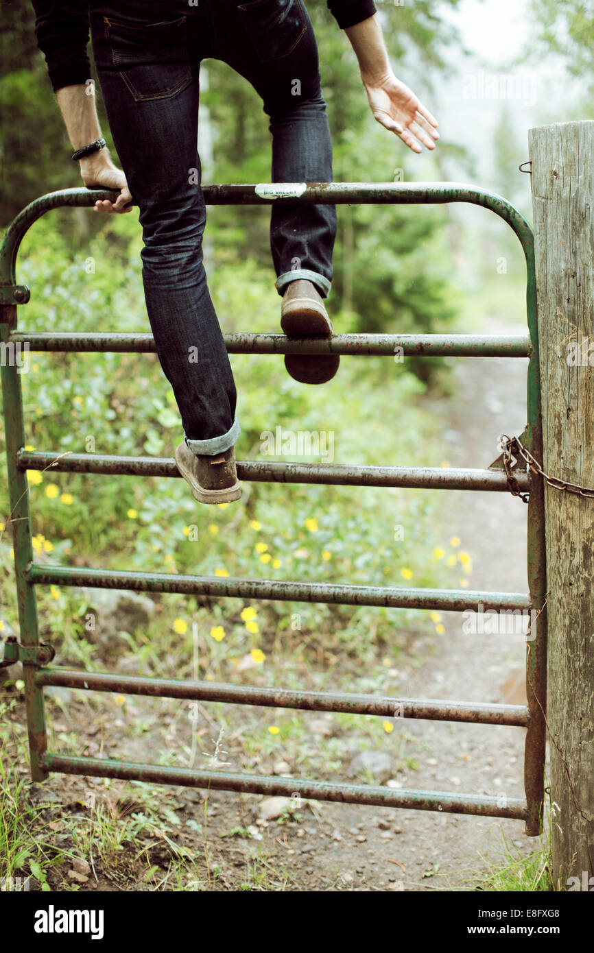 Man climbing over barrier Stock Photo - Alamy