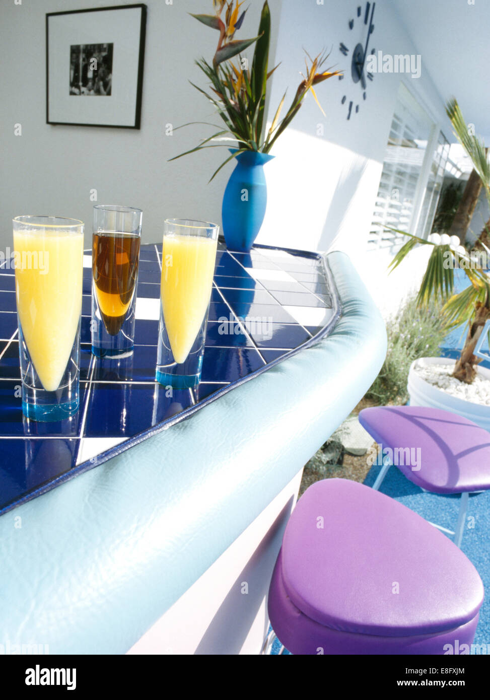 Glass of fruit juice on bar with purple stools on terrace of ...