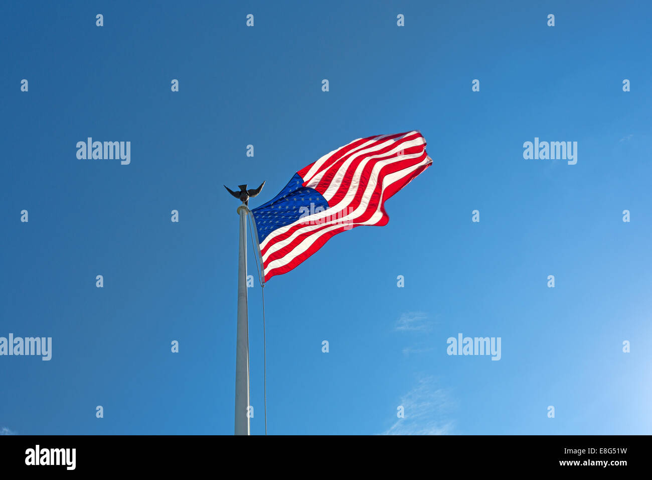 The American flag flapping in the wind against a blue sky with wispy ...