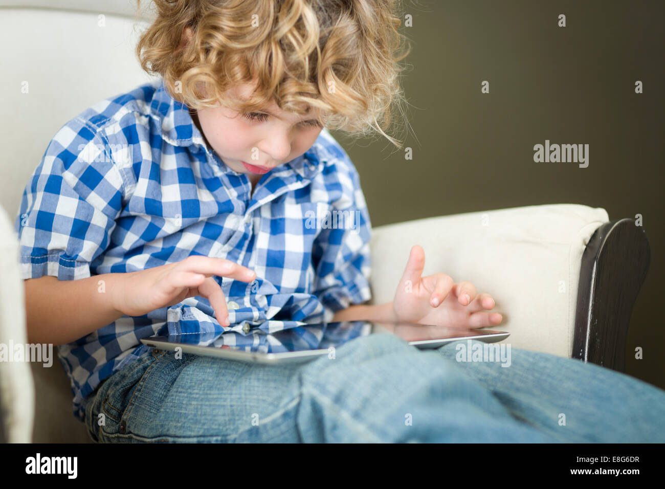 Cute Young Blond Boy Using His Computer Tablet in a Chair Stock Photo ...